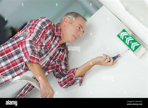 Man Fixing Illuminated Exit Sign To Wall Stock Photo Alamy