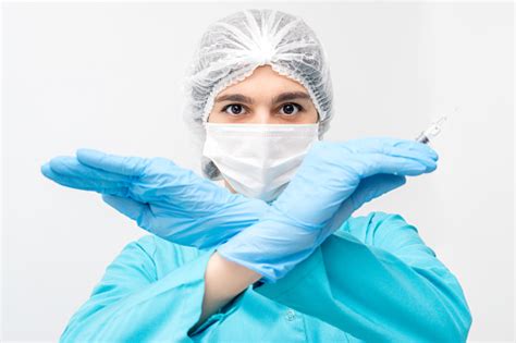 보호복을 입은 의료진의 초상화 장갑과 마스크를 들고 주사기를 들고 그녀의 손으로 금지된 제스처를 보여 준다 의학 및 의료 개념 코로나바이러스 예방 접종 개념 25 29세에