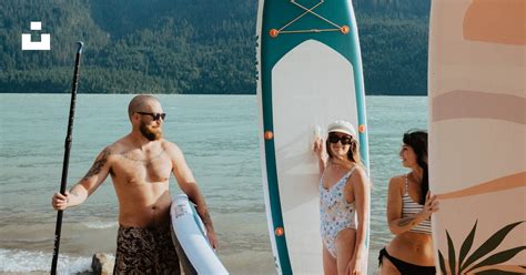 서핑보드 옆 해변에 서 있는 한 무리의 사람들 사진 Unsplash의 무료 패들 보드 이미지