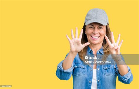 아름 다운 중 년 여자에 스포츠 모자를 쓰고 절연 배경 표시 하 고 자신감과 행복 미소 동안 9 번호 손가락으로 가리키는 가리키기에 대한 스톡 사진 및 기타 이미지 Istock