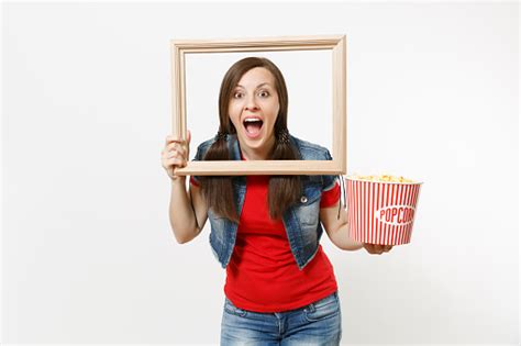 영화 영화를 보고 팝콘 및 그림 프레임 흰색 배경에 고립의 양동이 들고 캐주얼 옷에 젊은 재미 놀된 매력적인 갈색 머리 여자의 초상화 영화 개념에서의 감정