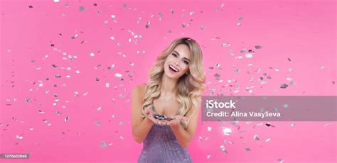 새해 생일 축하 멋진 이벤트 파티를 축하하는 여자 분홍색 배경에 색종이를 던지는 반짝이는 실버 드레스를 입은 아름다운 흥분한 미소 소녀의 초상화 텍스트 모형을 위한 공간을