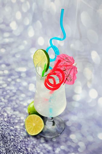 라임 슬라이스 칵테일 우산 빨대가 회색 추상적인 배경에 얼음을 곁들인 투명한 감귤 주스의 키가 큰 유리 감귤류 과일에 대한 스톡 사진 및 기타 이미지 Istock