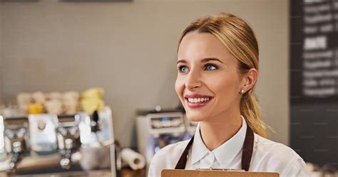 나무 테이블 근처에 서 있는 동안 멀리 바라보는 손에 클립보드를 들고 행복한 쾌활한 여성의 초상화를 닫습니다 사진 Unsplash의 계산대 이미지