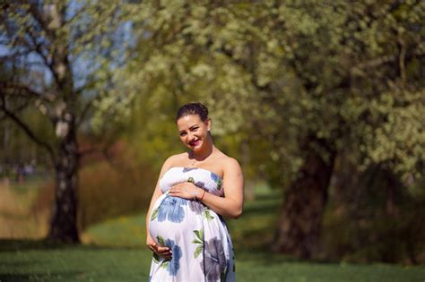 젊은 여행자 임신 한 여자 걷기 달리기 주위를 선회 하 고 꽃 패턴으로 여름 빛 긴 드레스를 입고 꽃 피는 사쿠라 벚꽃 나무 공원에서 그녀의 여가 자유 시간을 즐긴다 개념에