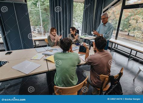 College Babes Collaborating In A Modern Classroom With Guidance From Professor Stock Photo