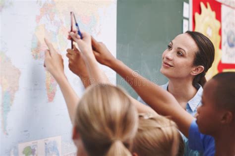 Showing Them Around A World Map An Excited Class Pointing At A World Map With Their Geography