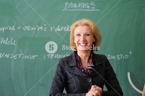 Teacher Smiling In Front Of A Chalkboard Royalty Free Stock Image