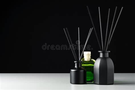 Two Black Reed Diffuser Bottles On A White Surface With Grey Background