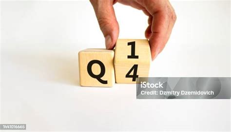 4 분기부터 1 분기까지의 상징 사업가는 나무 큐브를 돌리고 Q4라는 단어를 Q1로 바꿉니다 아름 다운 흰색 테이블 흰색 배경입니다 비즈니스 행복한 1분기 Q1 개념 복사