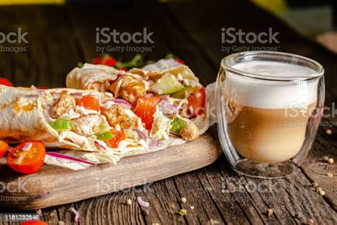 오래된 나무 테이블에 햄버거 또는 샤와르마와 육즙 샌드위치 도마에 위에서 촬영 측면에서 거품라적 라떼 카푸치노와 함께 가냘픈에