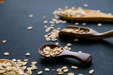 귀리 줄기 그리고 어두운 배경에 나무 숟가락에 귀리 플레이크 자연 빛입니다 선택적 초점입니다 검은 배경에 닫습니다 상위 뷰 평평