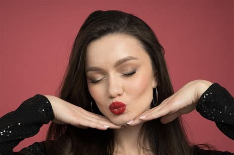 Premium Photo A Kiss Of A Pretty Brunette On A Red Background
