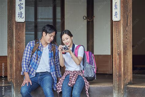 한국의 옛날 전통 가옥 건물을 배경으로 여행 또는 가이드 하고 있는 젊은 남녀 커플 또는 친구 아시아 모델 Photos