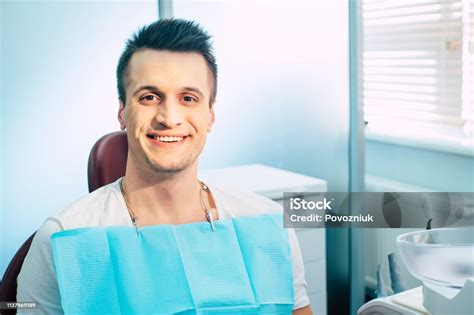 기뻤습니다 치과 의사 캐비닛의 밝은 창 바로 앞 치과의 자에 앉아 치과 진료소에서 그의 얼굴에 건강 하 고 흰 미소와 함께 좋은 찾고 남자 2명에 대한 스톡 사진 및 기타