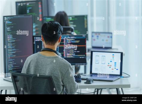 asian software developers working on multiple screens displaying code
