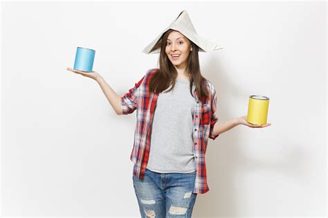 캐주얼 의류와 신문 모자 흰색 배경에 고립 된 페인트 깡통을 들고 젊은 웃는 아름 다운 여자 악기 재건축 아파트 룸 액세서리입니다 수리 가정 개념입니다 Diy에 대한 스톡