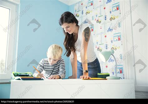 Mutter Hilft Sohn Bei Den Hausaufgaben Am Schreibtisch Lizenzfreies