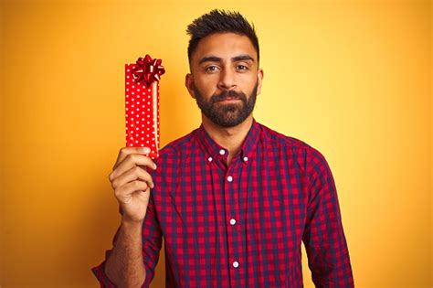 아랍 인도 히스패닉 남자 들고 발렌타인 선물 서 고립 된 노란색 배경 에 자신감 있는 표정으로 스마트 얼굴 생각 심각한 감정에 대한 스톡 사진 및 기타 이미지 Istock