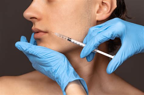 어두운 배경에 고립 된 주사기가있는 파란색 장갑을 착용 한 젊은 남성과 여성의 얼굴을 클로즈업합니다 화장품 충전 수술 절차 노화 방지 개념 20 24세에 대한 스톡 사진 및