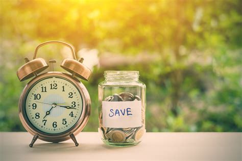 미래의 개념에 지속 가능한 생활을 위한 돈을 절약 빈티지 시계 근처와 투명 유리에 동전 항아리 절약은 돈을 지불 하는 세금 보험 건강 여행 등 교육에 대 한 저장
