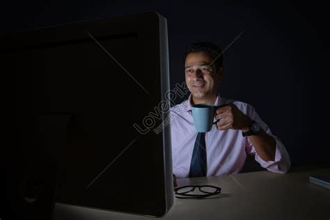 사무실에서 늦은 시간에 커피 한 잔을 들고 컴퓨터 작업을 하면서 웃고 있는 사업가 사진 사진 무료 다운로드 Lovepik