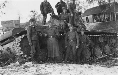 Немецкие солдаты рядом с подбитым в деревне советским танком КВ 1 — военное фото