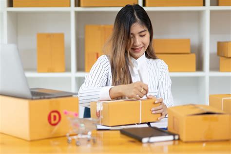 홈 오피스에서 일하는 작은 스타트업 비즈니스 여성의 여성이 노트북과 스마트폰으로 배송을 준비하기 위해 인터넷에서 주문을 확인합니다 20 24세에 대한 스톡 사진 및 기타