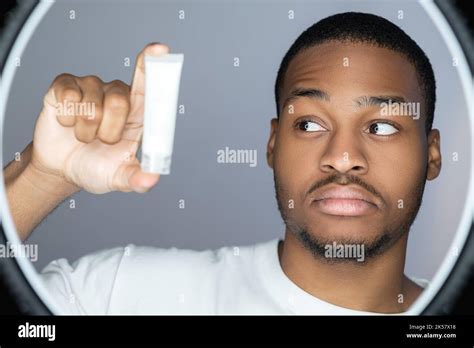 male facial care skin problem solution cosmetic product curious pensive african guy looking