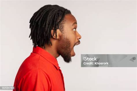 빨간 캐주얼 스타일의 티셔츠를 입은 공포의 수염을 기운 남자의 측면 보기 초상화는 입을 벌리고 서 충격적인 소식에 감명을 받았습니다 입 벌리기에 대한 스톡 사진 및 기타