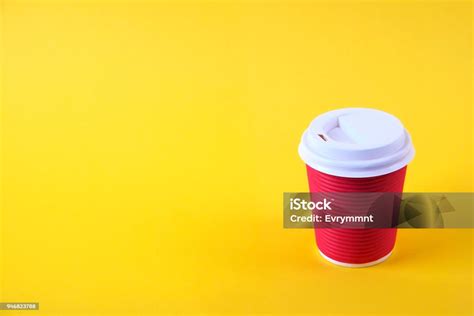 밝은 빨간색 일회용 안전 내 열 두 배 벽된 종이가 커피의 컵을 꺼내 뜨거운 음료 노란 배경에 백색 모자에 대 한 다채로운 에코친화적인 종이 얼굴 클로즈업 공간을 복사 0