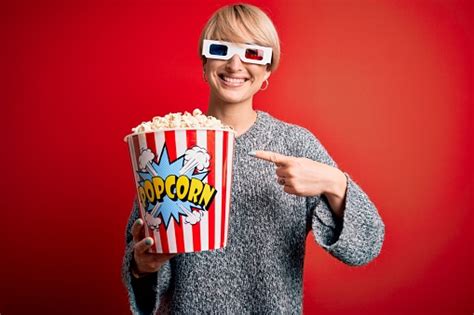 젊은 금발의 여자 와 짧은 머리 착용 3d 영화 안경 과 먹는 팝콘 에 The 영화관 에 대단히 행복 가리키는 손과 손가락 3차원 형태에 대한 스톡 사진 및 기타 이미지