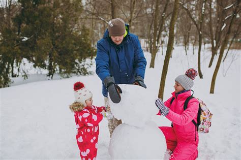 젊은 가족 여성 재생 눈 공원에서 눈사람을 만드는 따뜻한 옷을 겨울에 어린 소녀를 남자 또는 야외 숲 겨울 재미 휴일에 여 가입니다 사랑 관계 가족 사람들 라이프 스타일