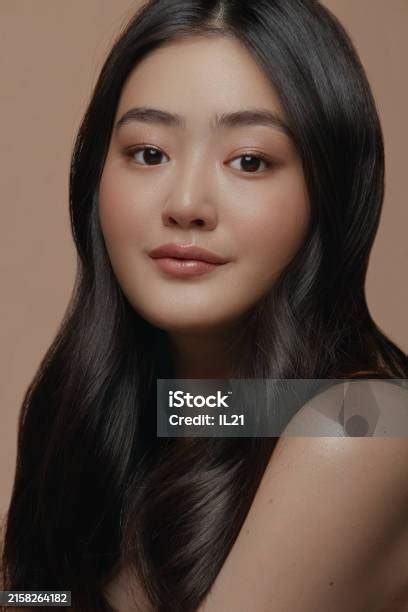 베이지 색 배경에 서 있는 건강하고 깨끗한 피부를 가진 아름 다운 아시아 여성 모델의 초상화를 세로로 클로즈업합니다 긴 머리에 대한 스톡 사진 및 기타 이미지 Istock