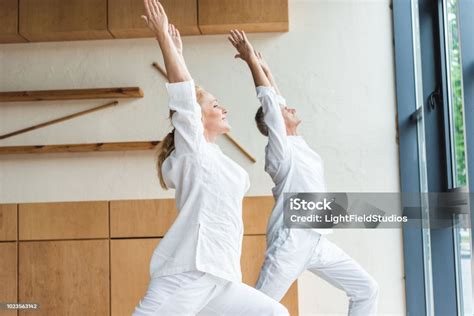 스포티 한 수석 몇 집에서 요가 연습 하는 동안 전사 포즈를 수행의 측면 보기 노인에 대한 스톡 사진 및 기타 이미지 노인 요가 가정 생활 Istock