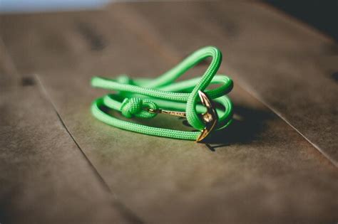premium photo close up of anchor pendant with green string on wooden