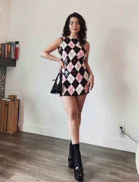 A Woman Standing In Front Of A White Wall Wearing A Black And Pink