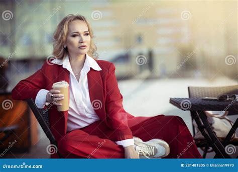 Blond Woman In Red Pant Suit And White Blouse Closeup Photo On Urban Glass Mirror Background