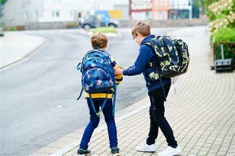 배낭이나 가방을 가진 두 명의 어린 소년 학교에 가는 길에 학생들 건강한 미소 짓는 아이들 형제와 가장 친한 친구는 집을 떠나는 거리에서 야외에서 학교로 돌아갑니다 행복한