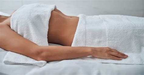 흰색 시트가 있는 데이베드에 누워 있는 가슴에 수건을 착용한 여성의 몸을 닫습니다 사진 Unsplash의 청년 성인 이미지