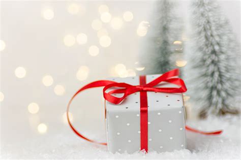 작은 우아한 실버 선물 상자 전나무 나무 눈 숲에서 겨울 장면에서 빨간 실크 리본으로 묶여 크리스마스 연말 휴가 마법의 분위기를