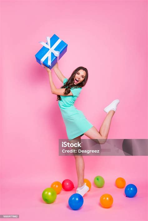 세로 전체 길이 다리 몸 아름 다운 곱슬 긴 머리 소녀 보유 선물 풍선 블루 드레스와 화이트 스 니 커 즈 선명한 분홍색 배경에 고립의 한가운데에 서 있는의 크기 초상화