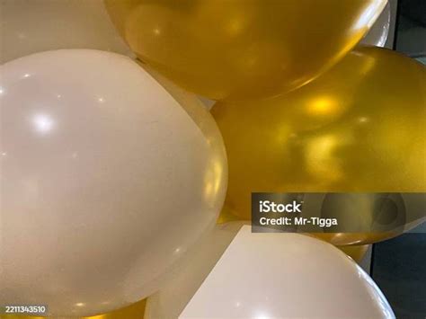 다양한 크기의 금색과 흰색 금속 풍선이 낮은 각도에서 찍은 간단한 사진 속에서 내부 벽을 배경으로 떠 있습니다 개념에 대한 스톡 사진 및 기타 이미지 Istock