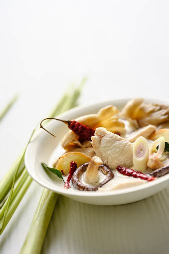 코코넛 밀크 톰 카 가이를 곁들인 세계적으로 유명한 태국 치킨이 흰색 나무 패널 테이블 배경에 레몬그라스와 함께 그릇에 담습니다 0명에 대한 스톡 사진 및 기타 이미지