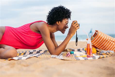스페인의 해변에서 휴식을 취하면서 카메라를 사용 하 여 사진을 찍는 젊은 흑인 여성 가정용 캠코더에 대한 스톡 사진 및 기타 이미지 가정용 캠코더 관광 관광객