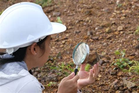 Female Geologist Using A Magnifying Glass Examines Nature Analyzing Rocks Or Pebbles