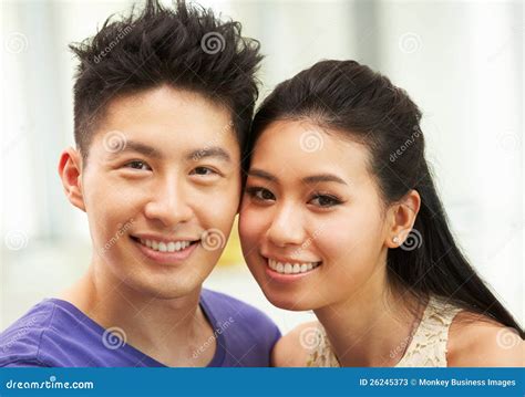 Молодые китайские пары ослабляя на софе дома Стоковое Изображение изображение насчитывающей