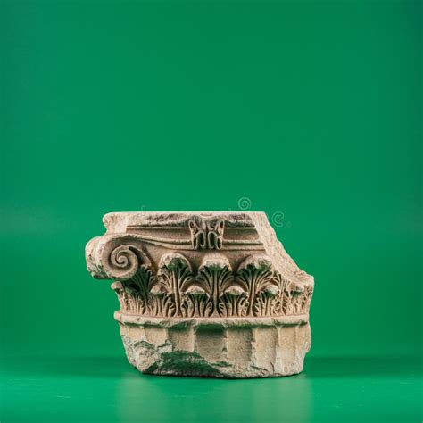 Fragment Of An Ancient Ionic Column Capital Against A Green Background