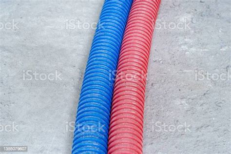 파란색과 빨간색 플라스틱 골판지 튜브가 바닥을 가로질러 뻗어 있습니다 건물의 수리 또는 건설 중에 열 및 물 공급의 임시 통신