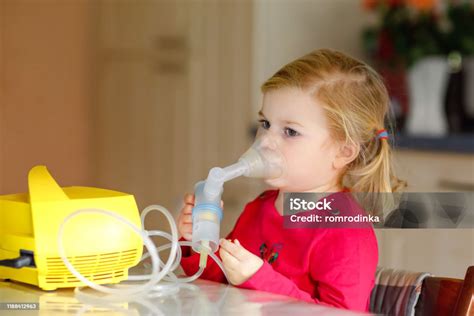 집에서 분무기로 흡입하는 어린 유아 소녀 장치를 들고 사랑스러운 아기 보육원에서 겨울 시간 후 독감과 기침을 가진 아이 천식 흡입기 흡입 증기 아픈 개념 들이마심에 대한